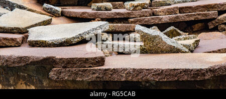 Broken concrete slabs on top of a crumbling, red sandstone wall Stock ...