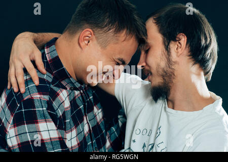 two guys hugging on a dark background Stock Photo - Alamy