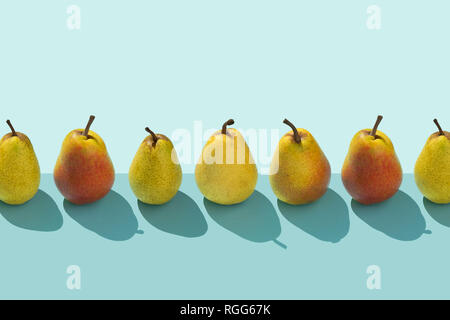 Multiple pears organized in a row over blue background Stock Photo - Alamy