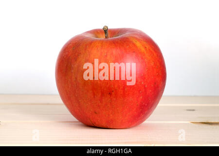 Big ripe red apple in beige wooden shelf on white background front view ...