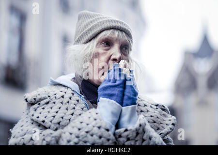 Poor homeless woman feeling very cold thus putting coat on head Stock ...