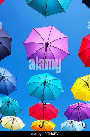 A low-angle shot of colorful umbrellas hanging from wires in an urban ...