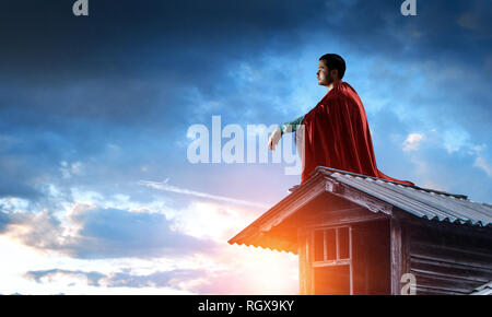 Thoughtful man in cape sitting on top of building. Mixed media Stock ...