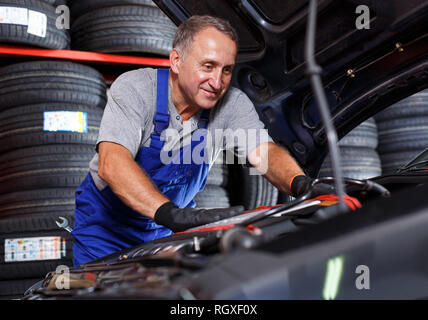 Professional mature man car mechanician repairing car in auto repair ...