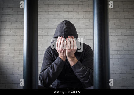 A prisoner in his cell behind bars in prison. Picture posed by model ...