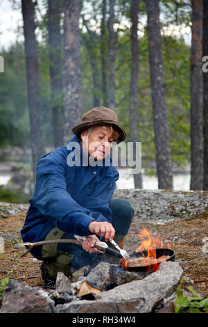 Woman cooking over an open fire in her basic rural village kitchen, The ...