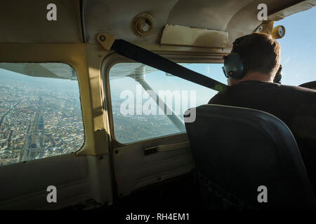 Small Airplane flying over the city during a vibrant winter sunset ...