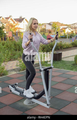 Woman Exercising On Elliptical Machine In Gym Stock Photo - Alamy