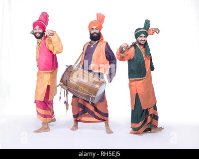 PORTRAIT OF A GROUP OF THREE BHANGRA DANCERS DANCING WITH WOODEN SNAKE ...