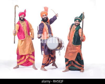 PORTRAIT OF A GROUP OF THREE BHANGRA DANCERS DANCING WITH WOODEN SNAKE ...