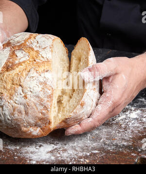 cook in a black tunic holds fresh baked bread, close up Stock Photo - Alamy