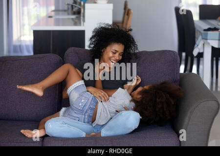 cheerful woman tickling african american boyfriend laughing in bedroom Stock Photo - Alamy