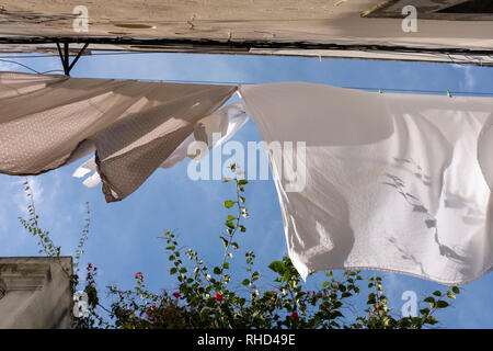 Pure white sheets hanging out to dry on a windy day on a washing line ...