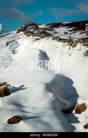 View of pile snowy drifts in the small town with children Munising ...