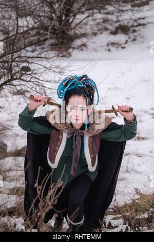Scared Viking woman with a sword in a black long mantle with fur ...