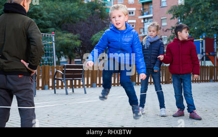 Children jump through an elastic rope in a children playground Stock ...