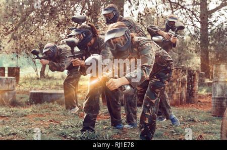 Expressive paintball team running with a marker guns at open playing ...