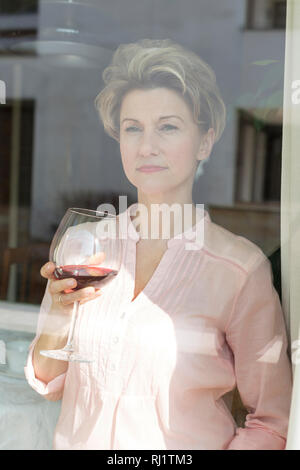 Thoughtful mature woman drinking wine while looking away at home Stock ...