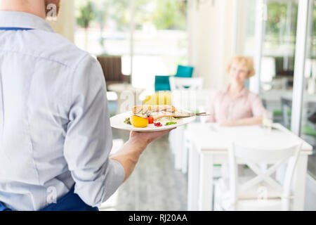 People sitting at restaurant table, waiter pouring white wine Stock ...