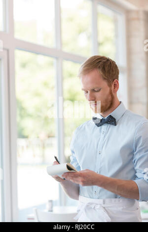 Waiter standing with notepad Stock Photo - Alamy