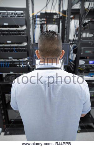Black Data Center IT Technician Standing in Server Rack Corridor with a ...