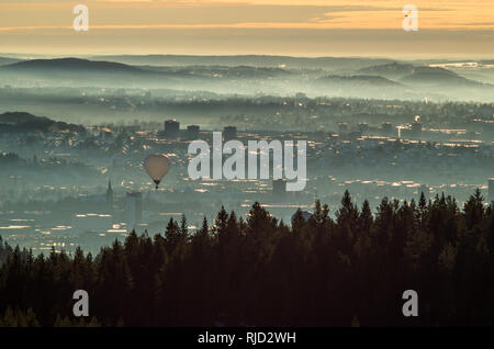 Hot air baloons flying over Oslo hidden in smog or fog in winter calm ...