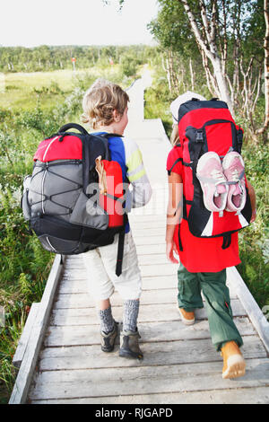 Two children with backpacks walking together up outdoor stairs ...