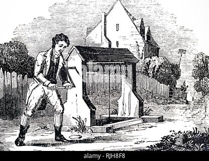 Man raising bucket of water from a well by turing crank handle and ...