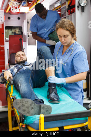 Emergency doctors providing medical care to injured man in ambulance ...