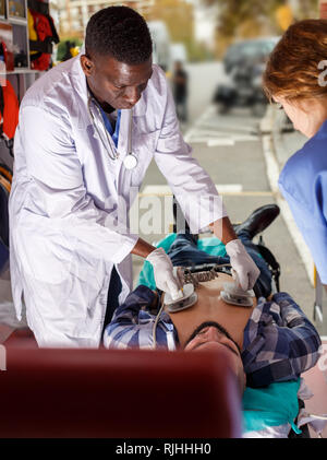 Rescue team making defibrillation to patient in ambulance car Stock ...