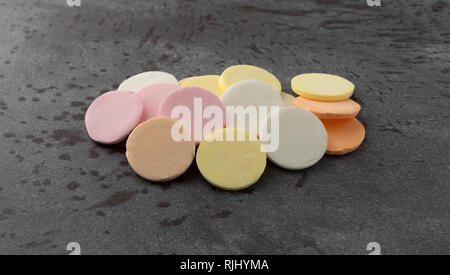 Top view of several thin colorful candy wafers on a gray background ...