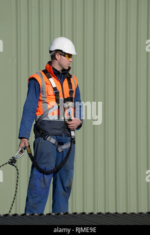 A builder wearing a safety harness while working at heights waits for ...