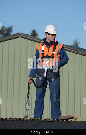 A builder wearing a safety harness while working at heights waits for ...