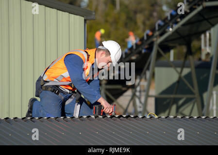 A builder wearing a safety harness while working at heights waits for ...