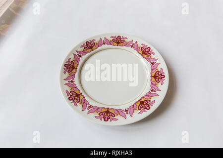 a white round plate with floral and line pattern on white background ...