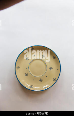 a yellow round plate with floral and line pattern on white background ...