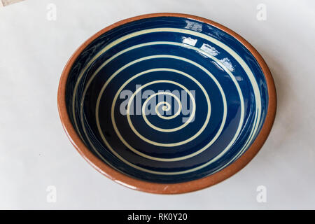 a blue round bowl with floral and line pattern on white background ...
