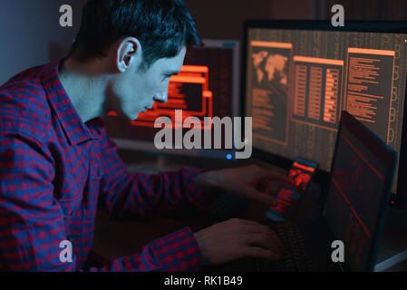 The male hacker in the hood is pointing his finger at the display ...