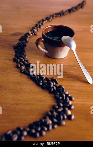 a cup with coffee beans stands on a saucer on a gray background close ...