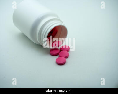 Red tablets are poured from a white plastic jar. Photo on white ...