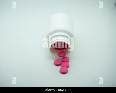 Red tablets are poured from a white plastic jar. Photo on white ...