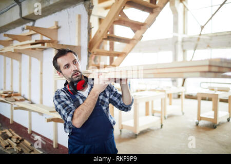 Man builder carrying wooden planks in construction site Stock Photo - Alamy