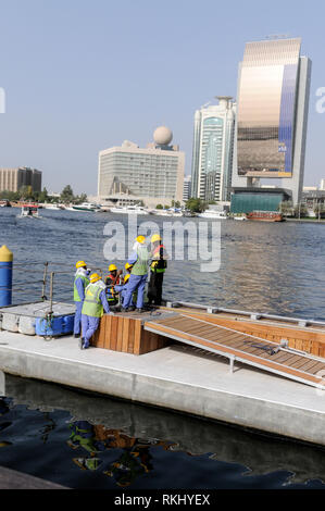 Asian construction workers on a floating platform on the Dubai Creek in ...