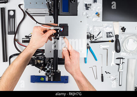 young man student assembly of 3D printer building kit on white table ...