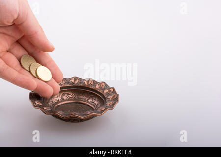 Hand giving away money to a metal bowl Stock Photo - Alamy