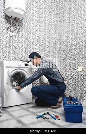 working man plumber repairs a washing machine in laundry Stock Photo ...