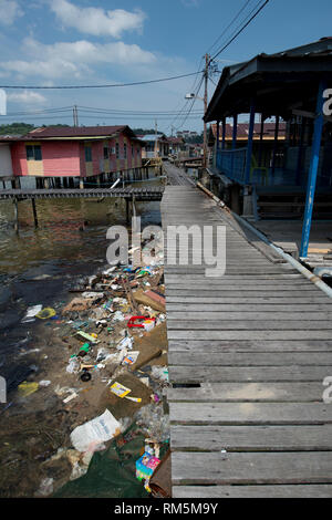 Garbage, by walkway and shack on stilts with washed up rubbish from ...