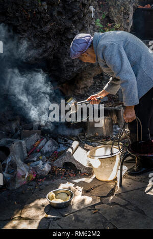Elderly woman cooking on open fire, Yunnan province, China Stock Photo ...