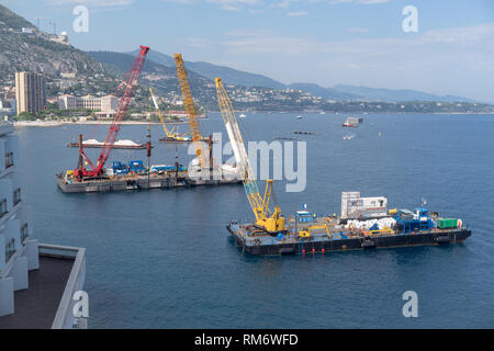 A construction crane barges begins land reclamation work off the coast ...