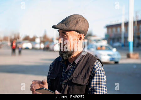An older Asian man using a phone to photograph native Moorhens ...